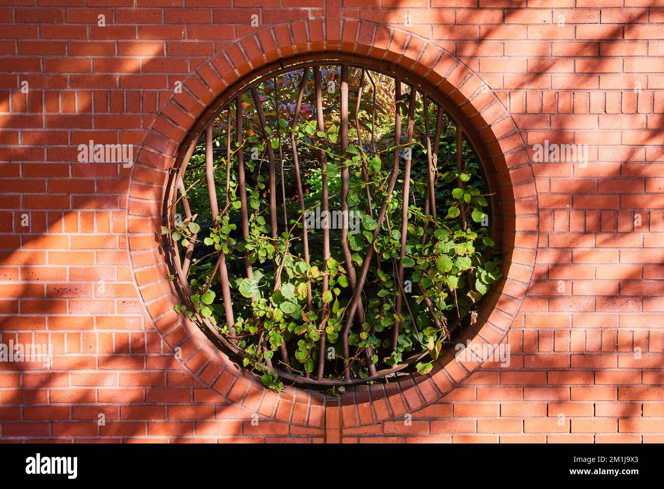 Brick wall with circle opening blocked by abstract steel bars and ...