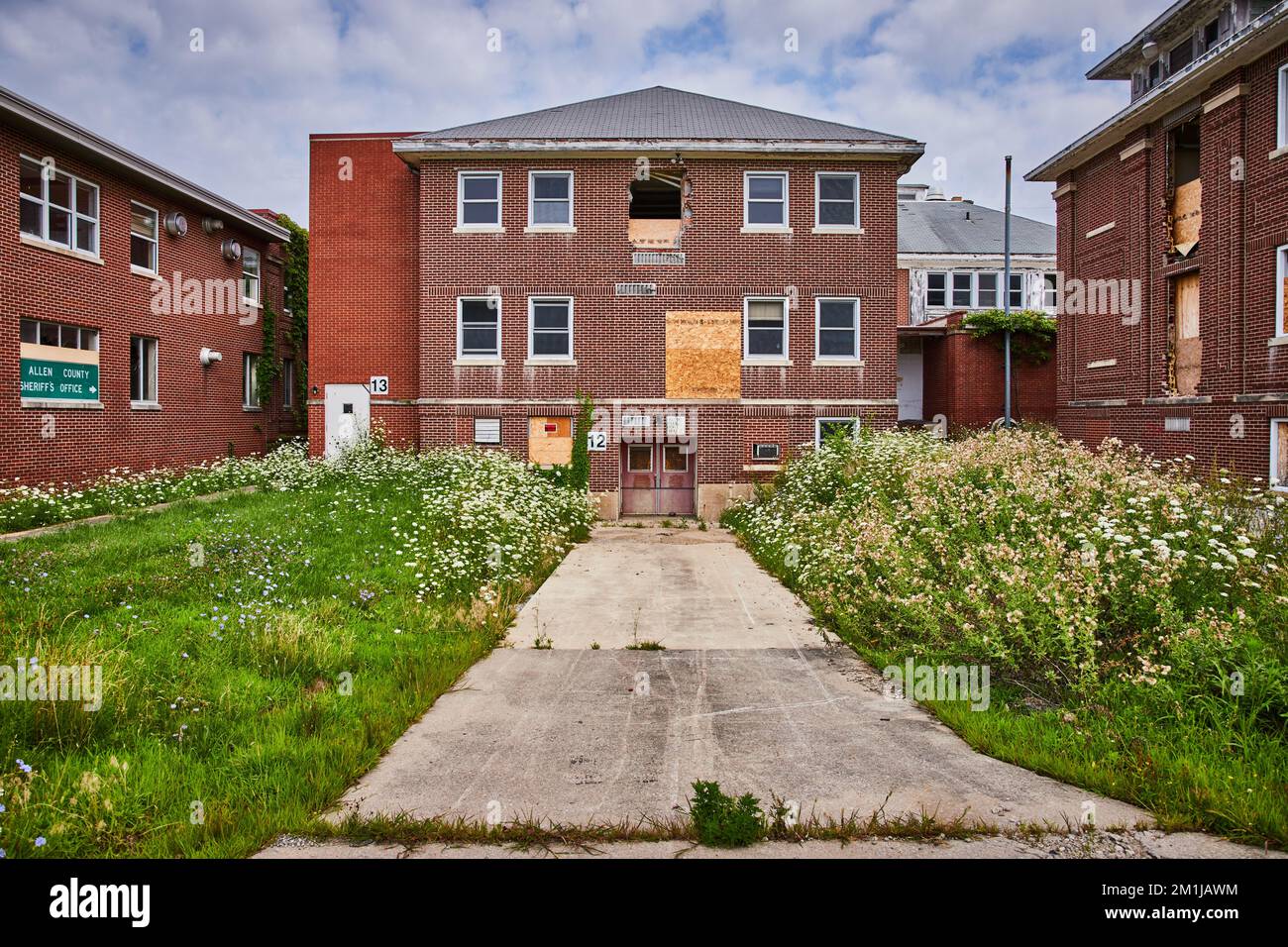Cement path leading to entrance of large abandoned brick hospital ...