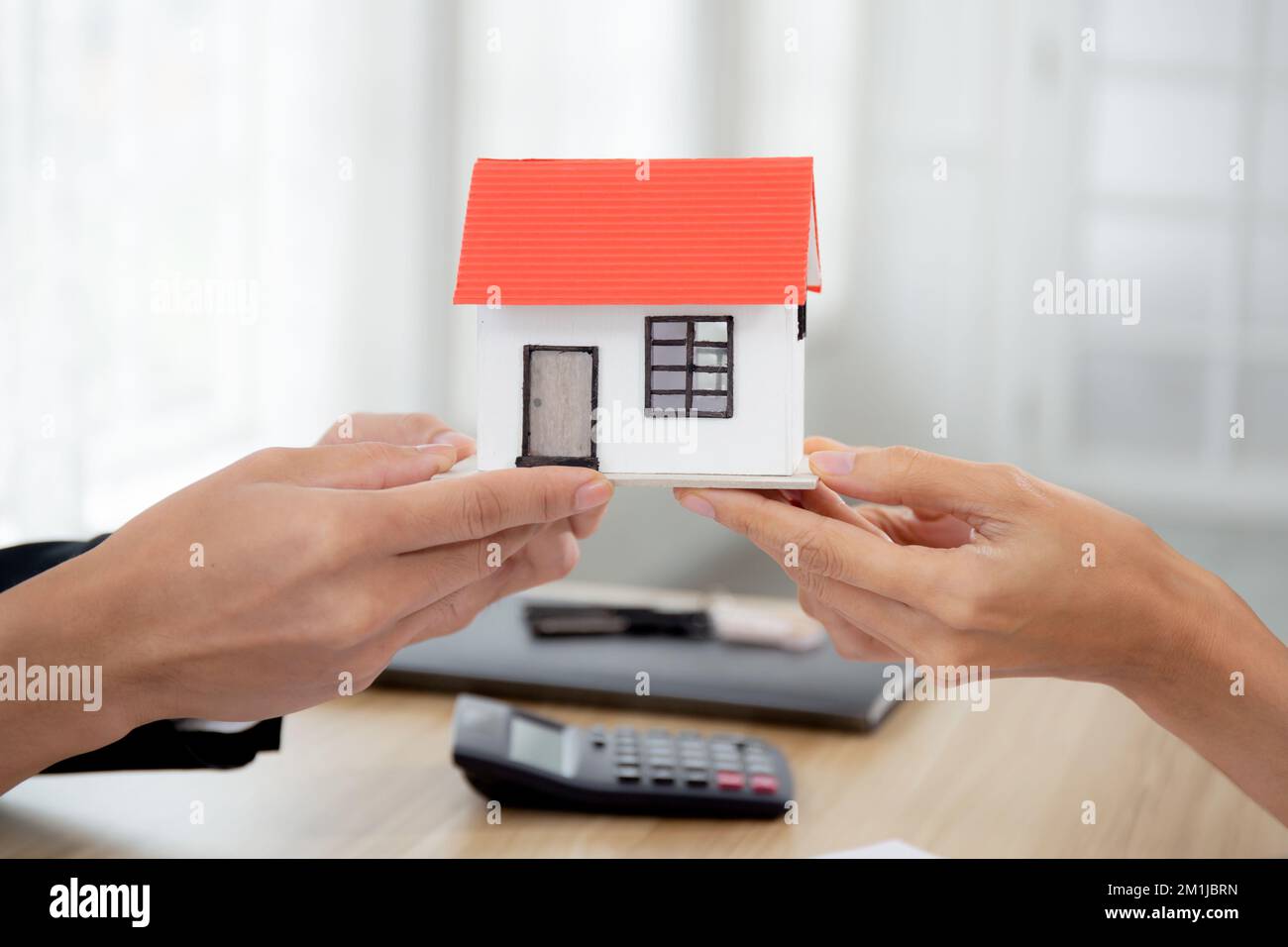 Closeup hands of young realtor man real estate giving house model to ...