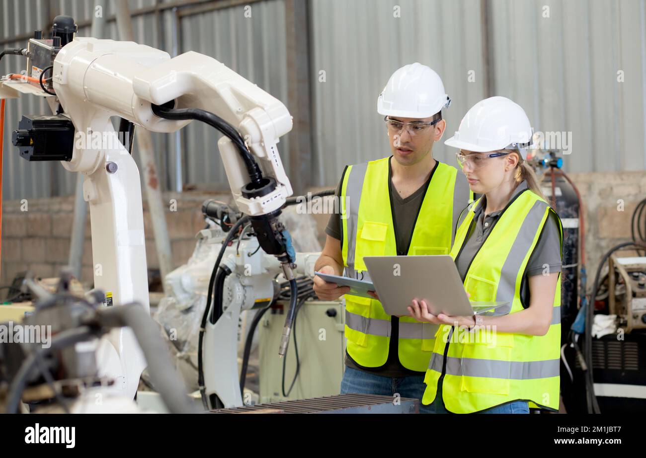Engineer man and woman talking and explaining about robot arms ...