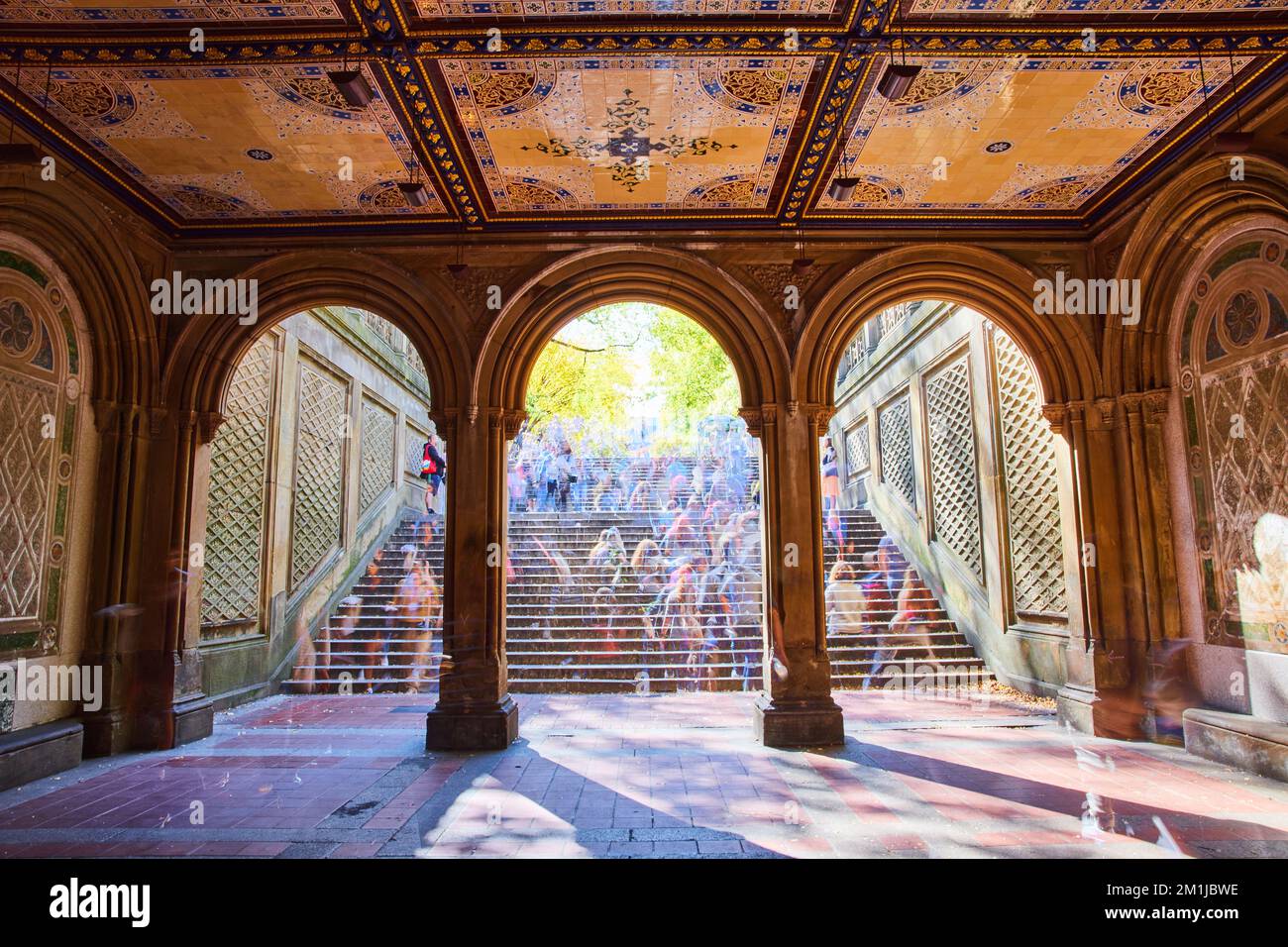 Crowded Central Park staircase through limestone arches with murals on ...