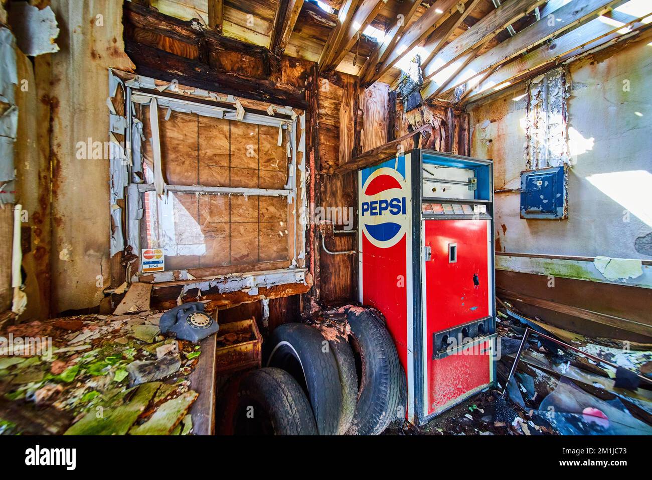 Destroyed interior of abandoned space with Pepsi vending machine, tires ...