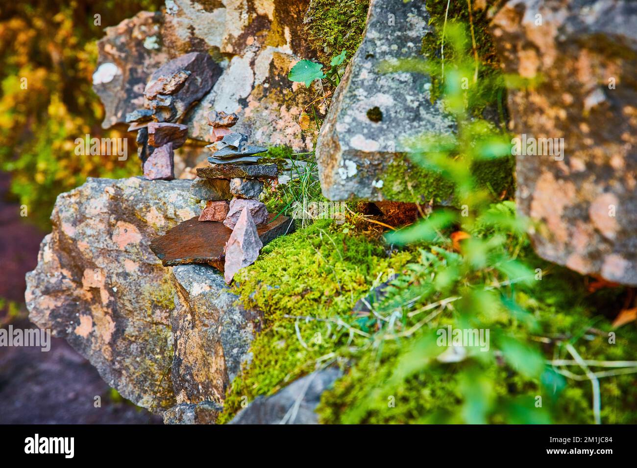 Stone wall at angle with cairn stone stack piles tiny in background and ...