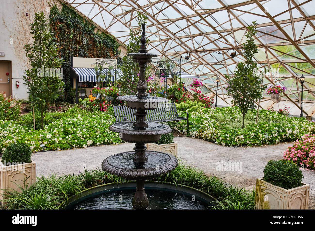 Multi-tiered black fountain inside of botanical gardens with glass roof ...