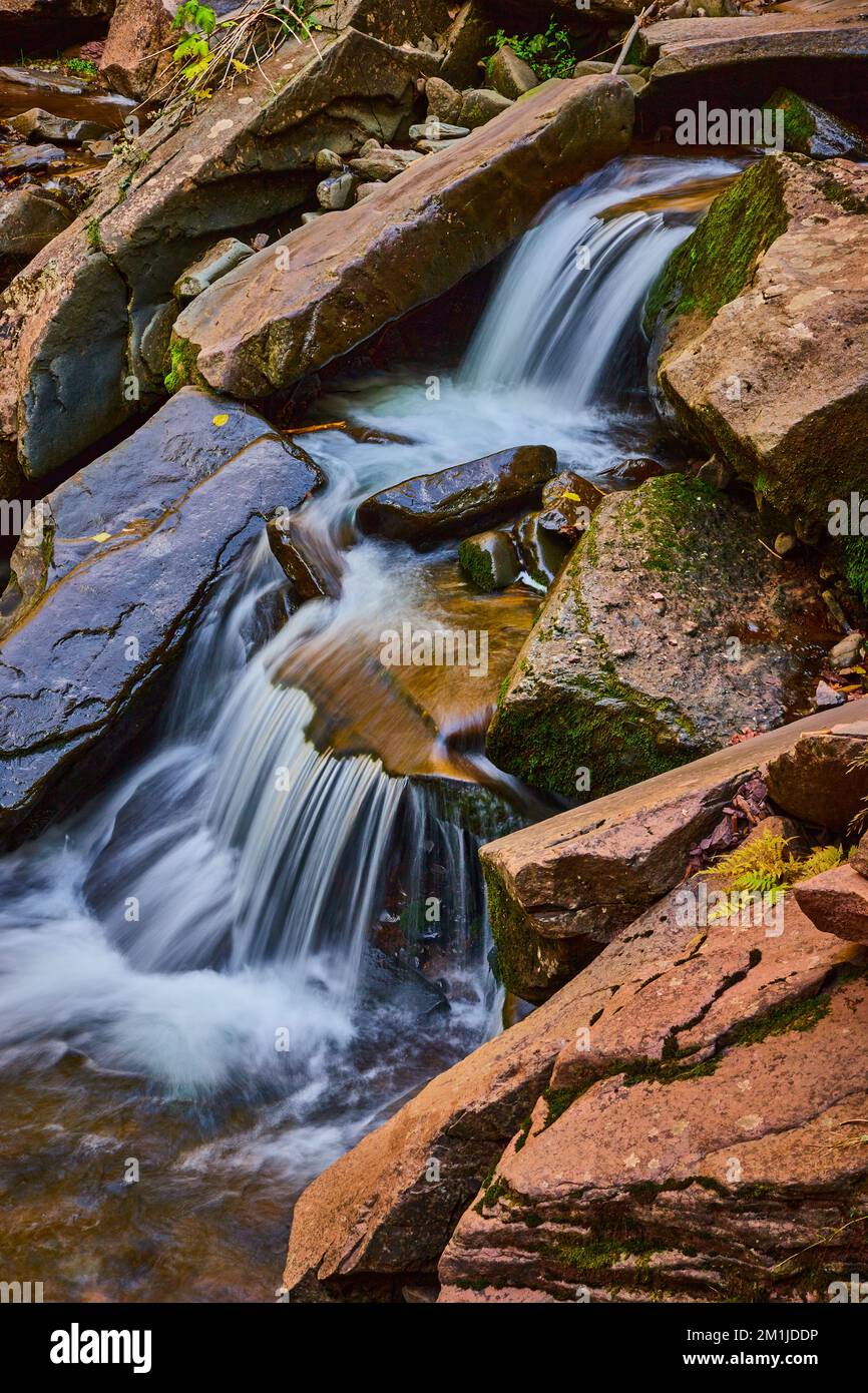 Detail of pair of small cascading waterfalls pouring over mossy ...
