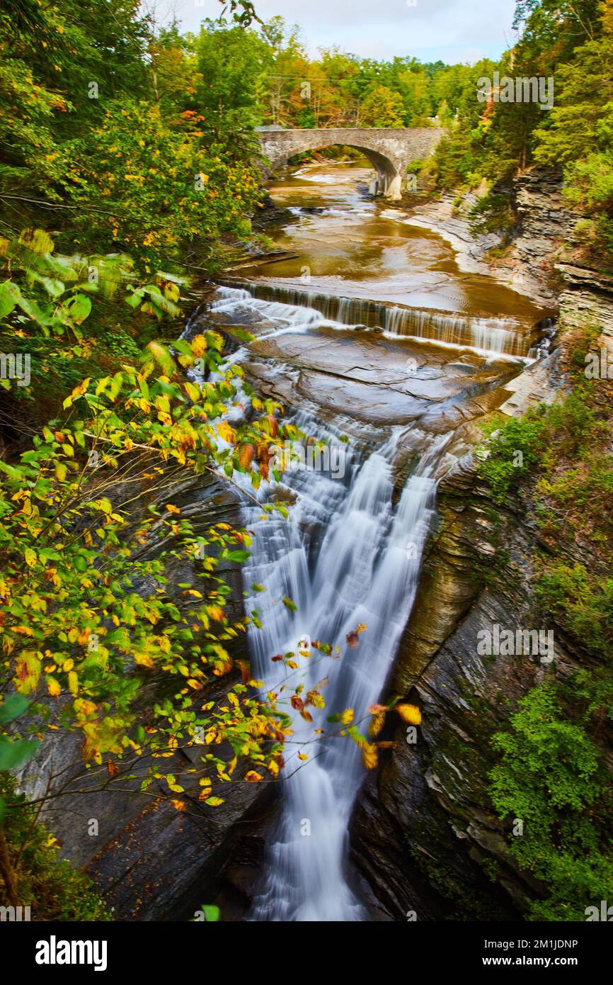 Waterfall into deep gorge with fall foliage, forest, and stone arched ...
