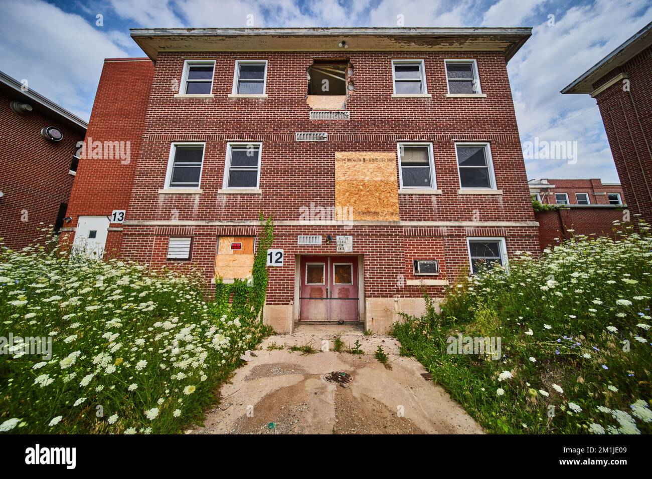Back entrance to huge abandoned brick building hospital with broken and ...