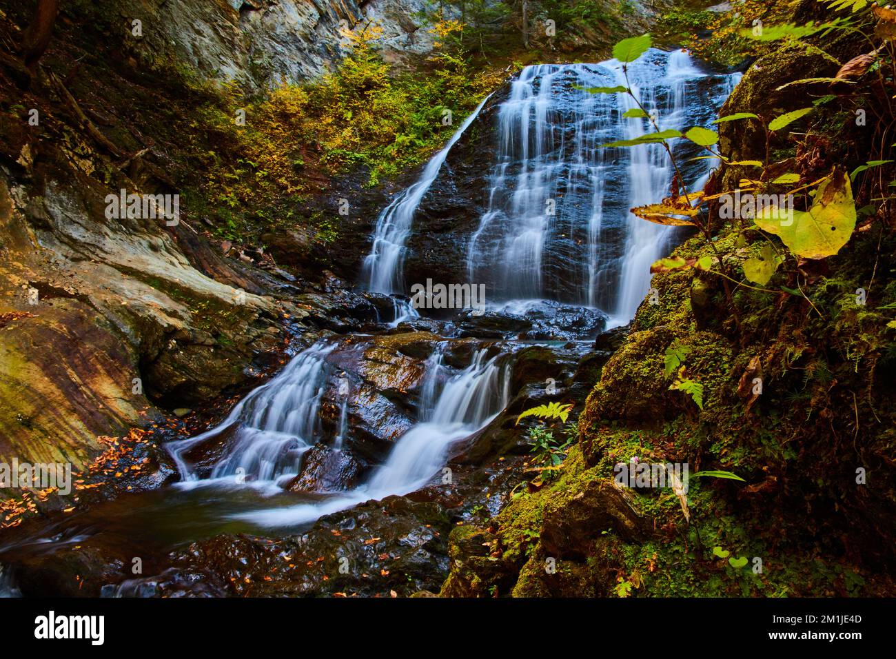 Large raging waterfall in tight gorge surrounded by mossy rocks and ...