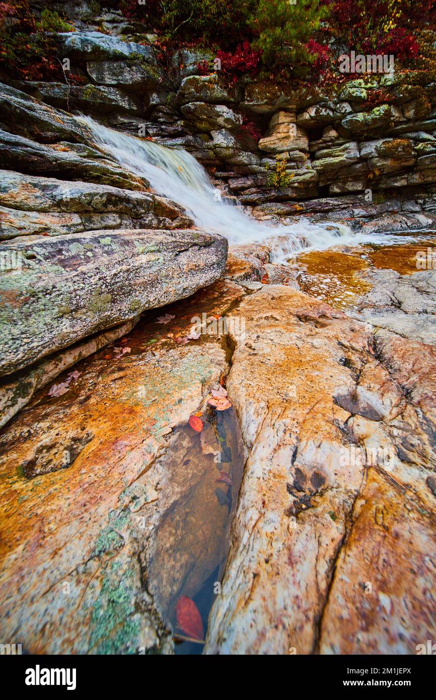 View of rocks in riverbed with puddle of water and waterfall in ...