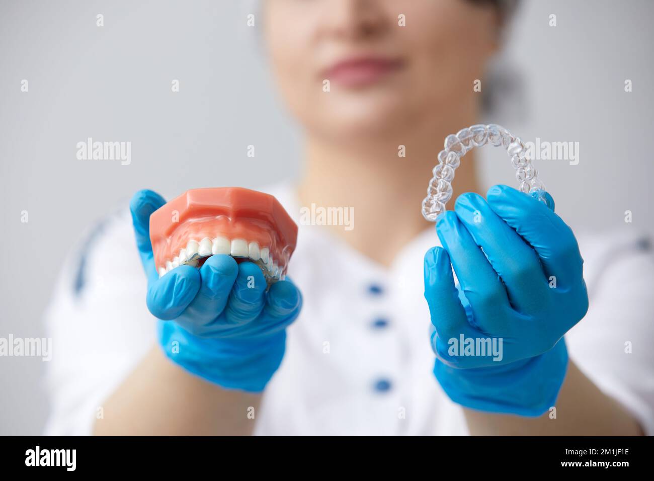 Orthodontist showing model of human jaw with wire braces and aligners ...