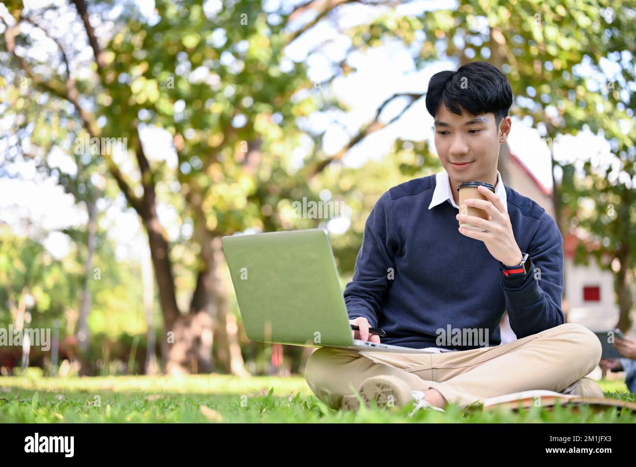 Handsome and smart young Asian male college student using laptop ...