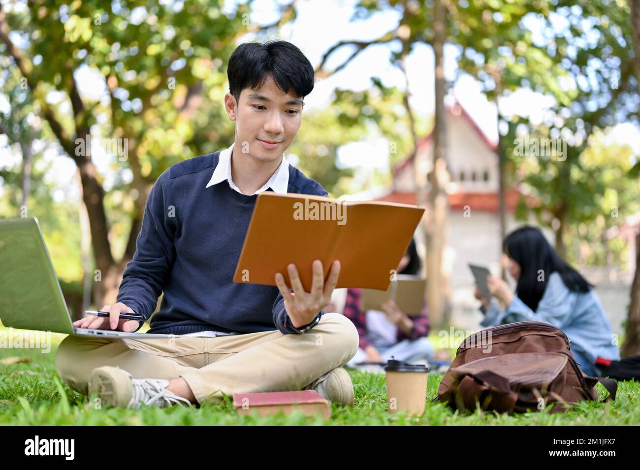 Smart and handsome young Asian male college student reading a book ...