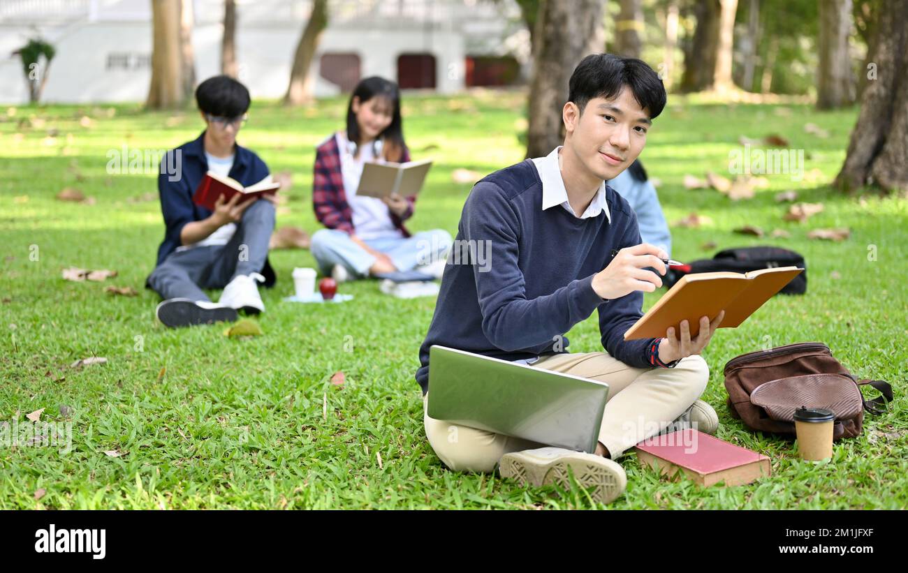Handsome and smart young Asian male college student doing homework in ...