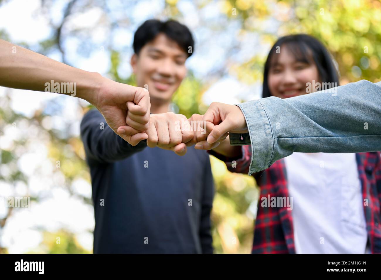 Cheerful young Asian college students showing fist bump together ...