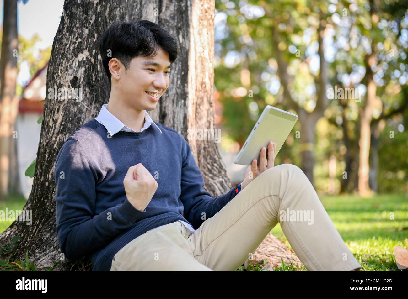 Happy and smart young Asian male college student using his digital ...