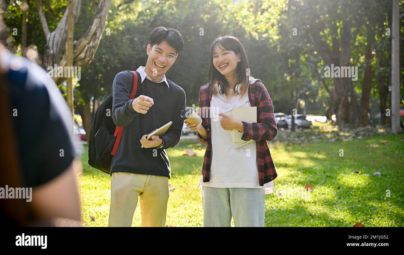 Cheerful and happy young Asian college students enjoy talking and ...