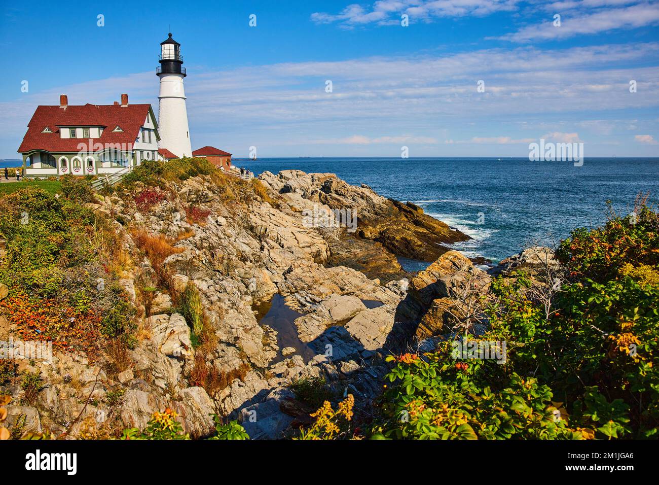 Classic white lighthouse in Maine overlooks the ocean on rocky coasts ...