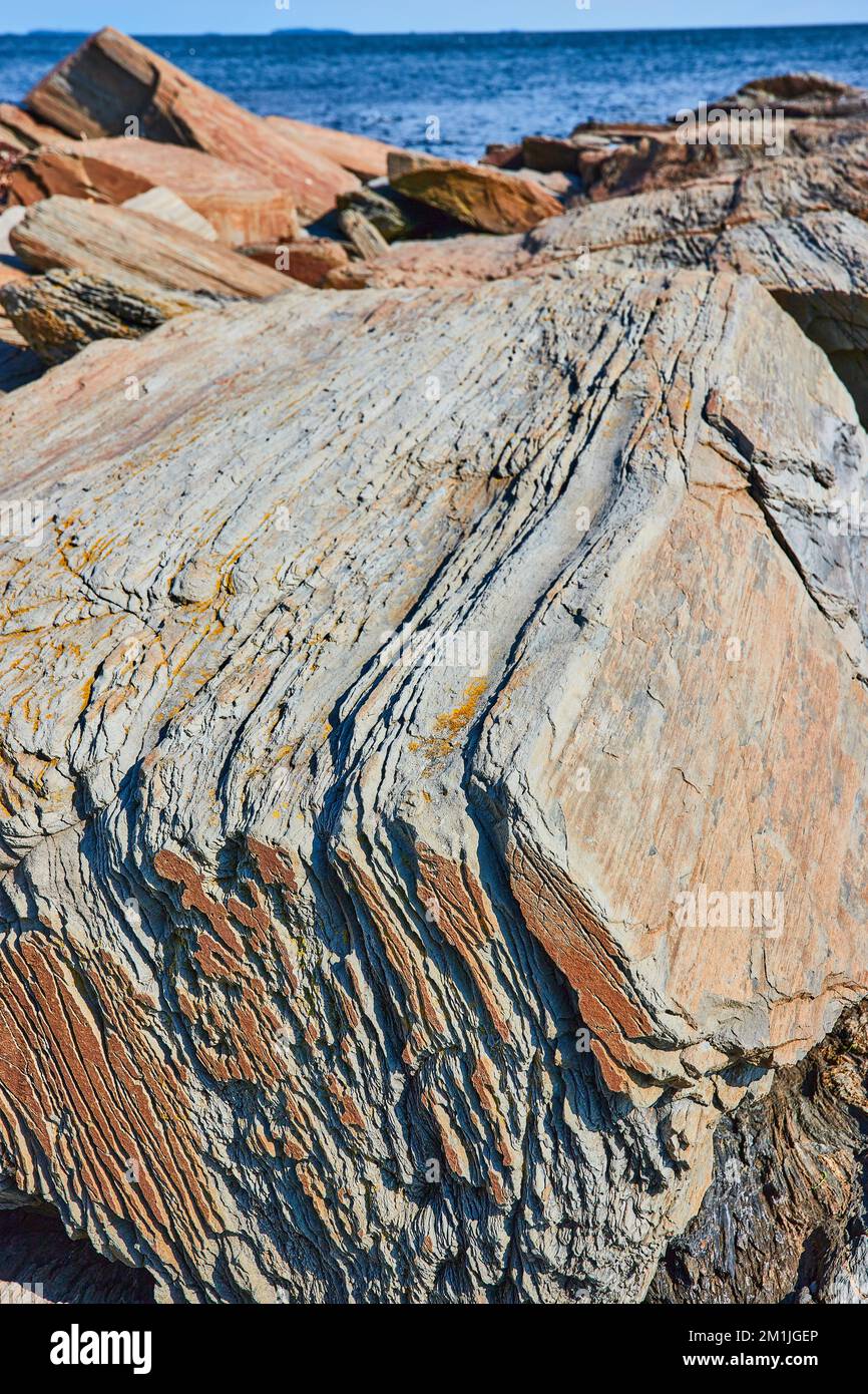 Unusual rock formations on Maine coast with sheets of layers and orange ...