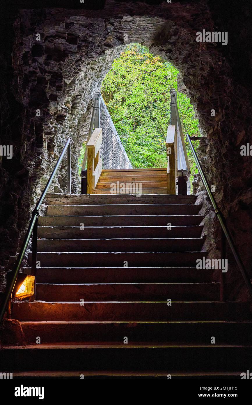 Stone steps in dark cave tunnel leading to exit with green forest Stock ...