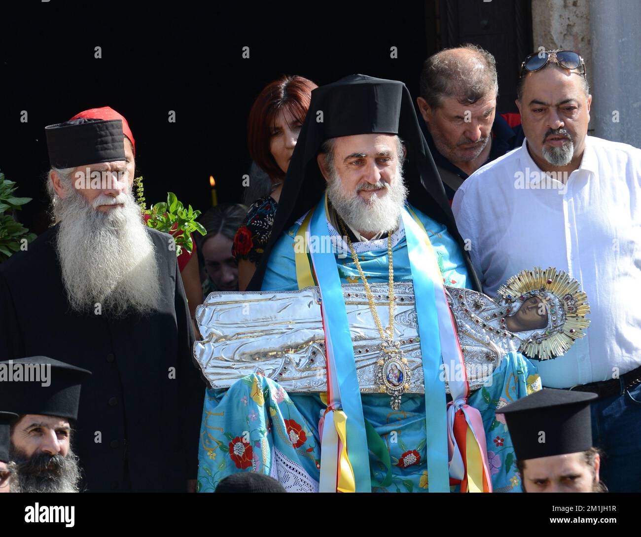 A Greek Orthodox priest carrying a silver icon of the Virgin Mary ...