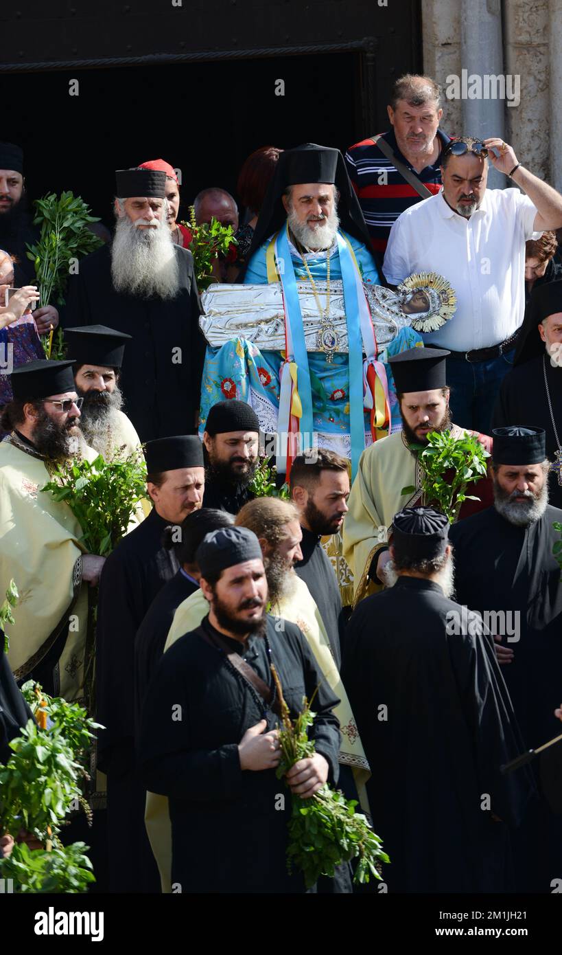 A Greek Orthodox priest carrying a silver icon of the Virgin Mary ...