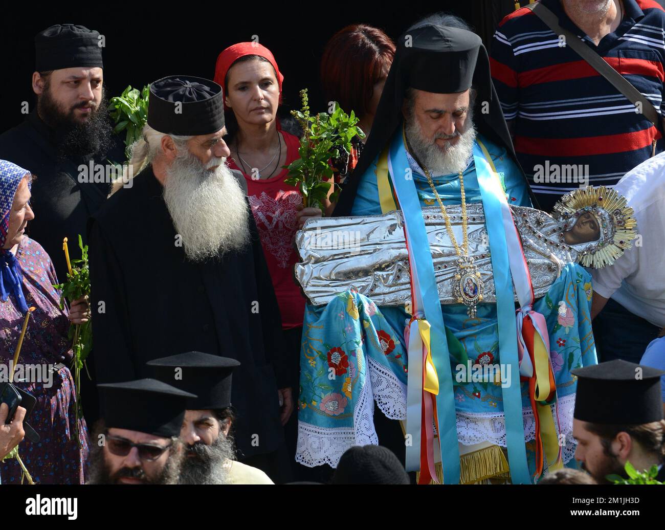 A Greek Orthodox priest carrying a silver icon of the Virgin Mary ...