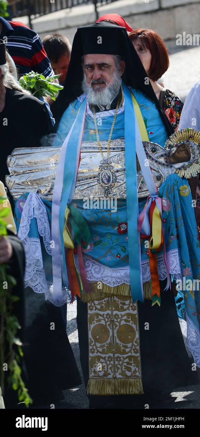 A Greek Orthodox priest carrying a silver icon of the Virgin Mary ...