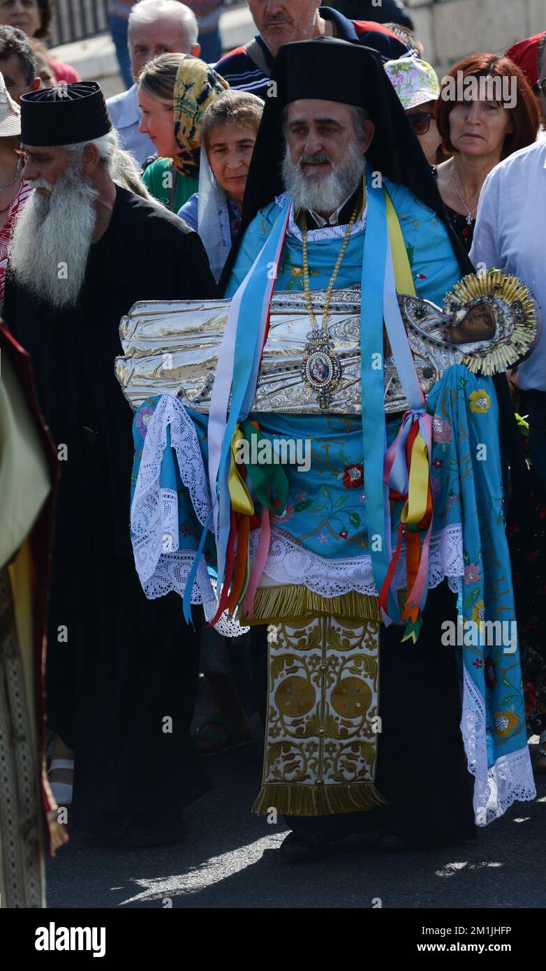 A Greek Orthodox priest carrying a silver icon of the Virgin Mary ...