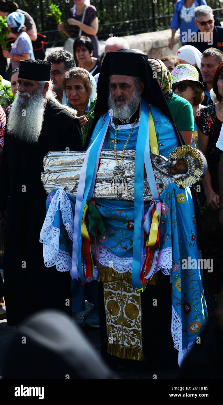 A Greek Orthodox priest carrying a silver icon of the Virgin Mary ...