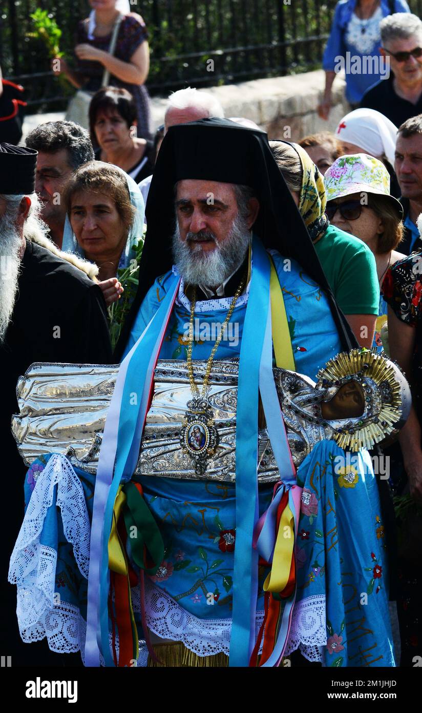 A Greek Orthodox priest carrying a silver icon of the Virgin Mary ...