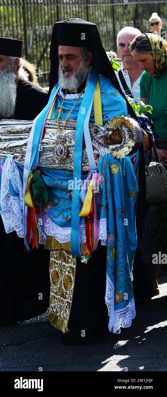 A Greek Orthodox priest carrying a silver icon of the Virgin Mary ...