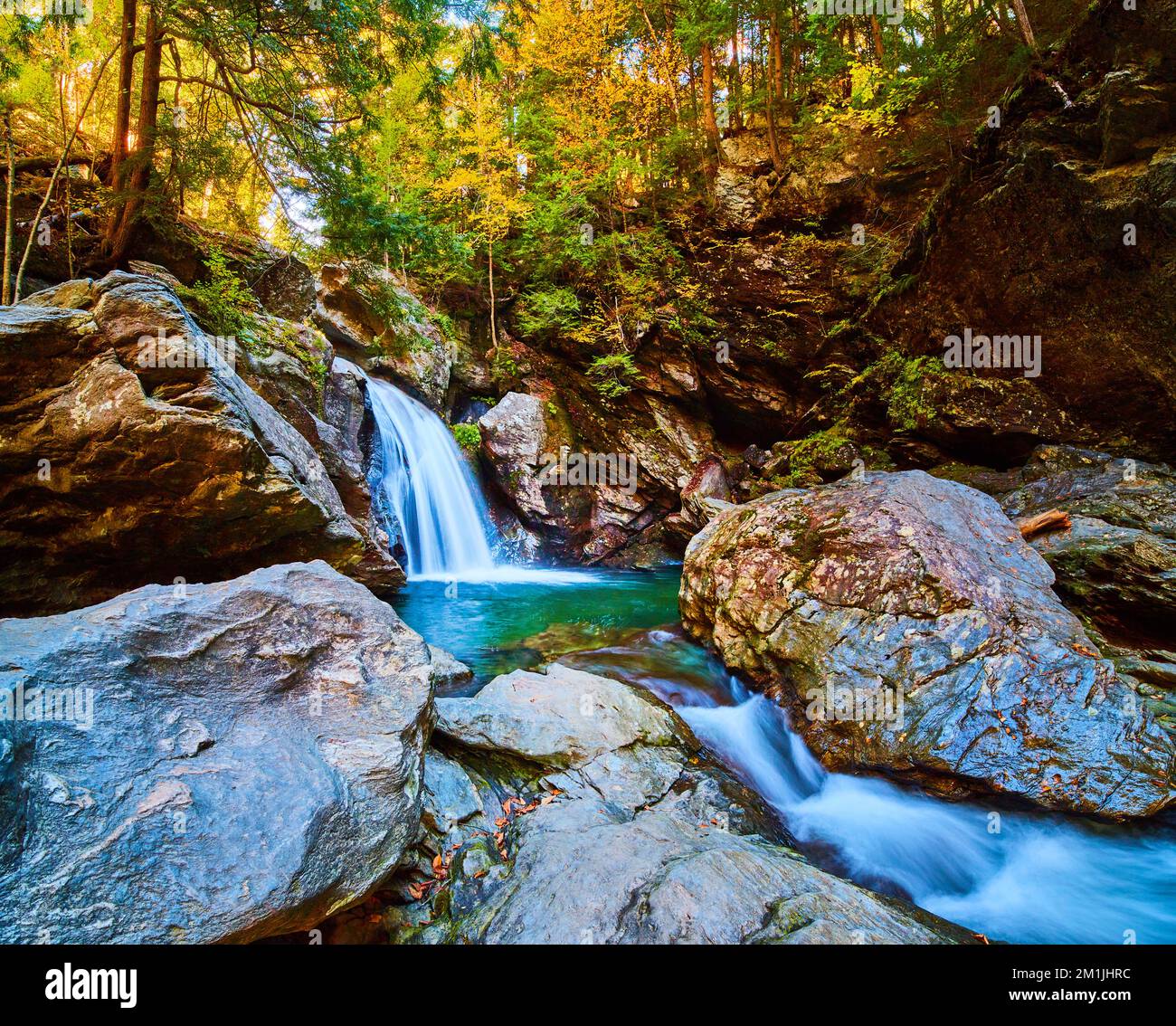 Magical blue waterfall pouring into pool of water surrounded by vibrant ...