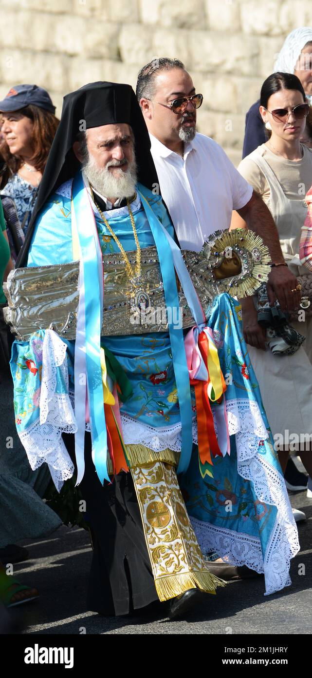 A Greek Orthodox priest carrying a silver icon of the Virgin Mary ...