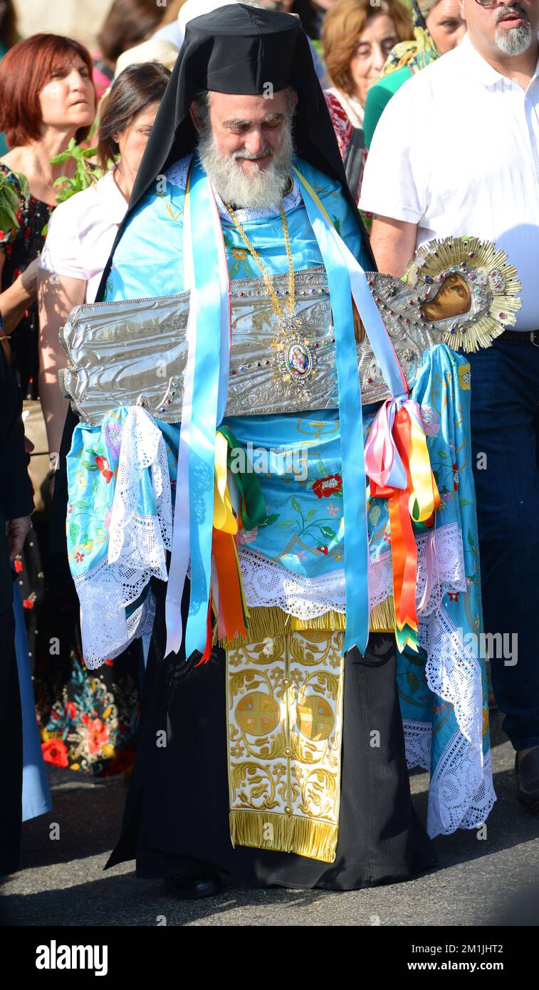 A Greek Orthodox priest carrying a silver icon of the Virgin Mary ...