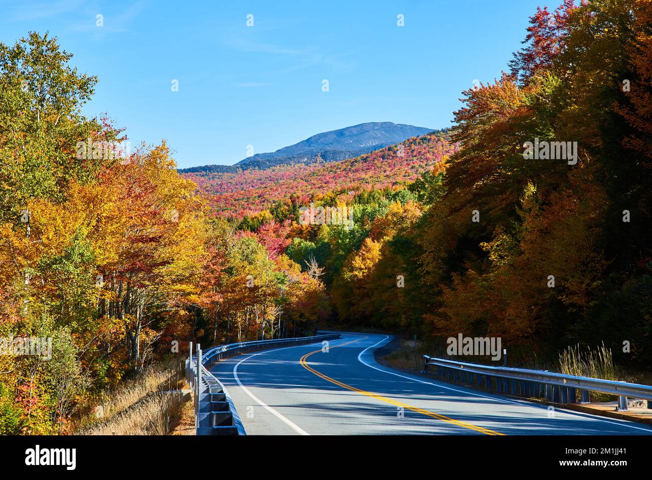 Looking down road from side in mountains during peak fall with colorful ...