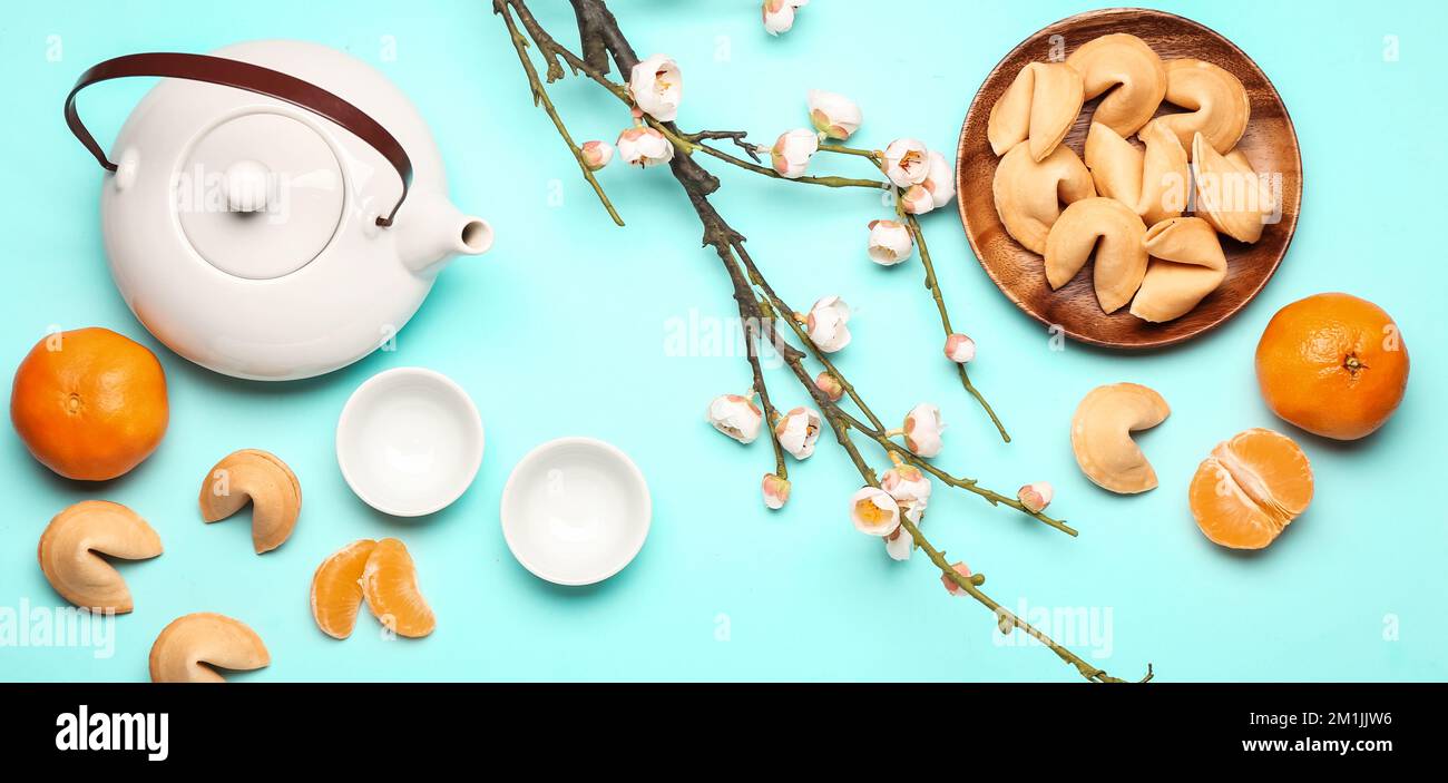 Tasty fortune cookies with tangerines and Chinese tea on light blue ...