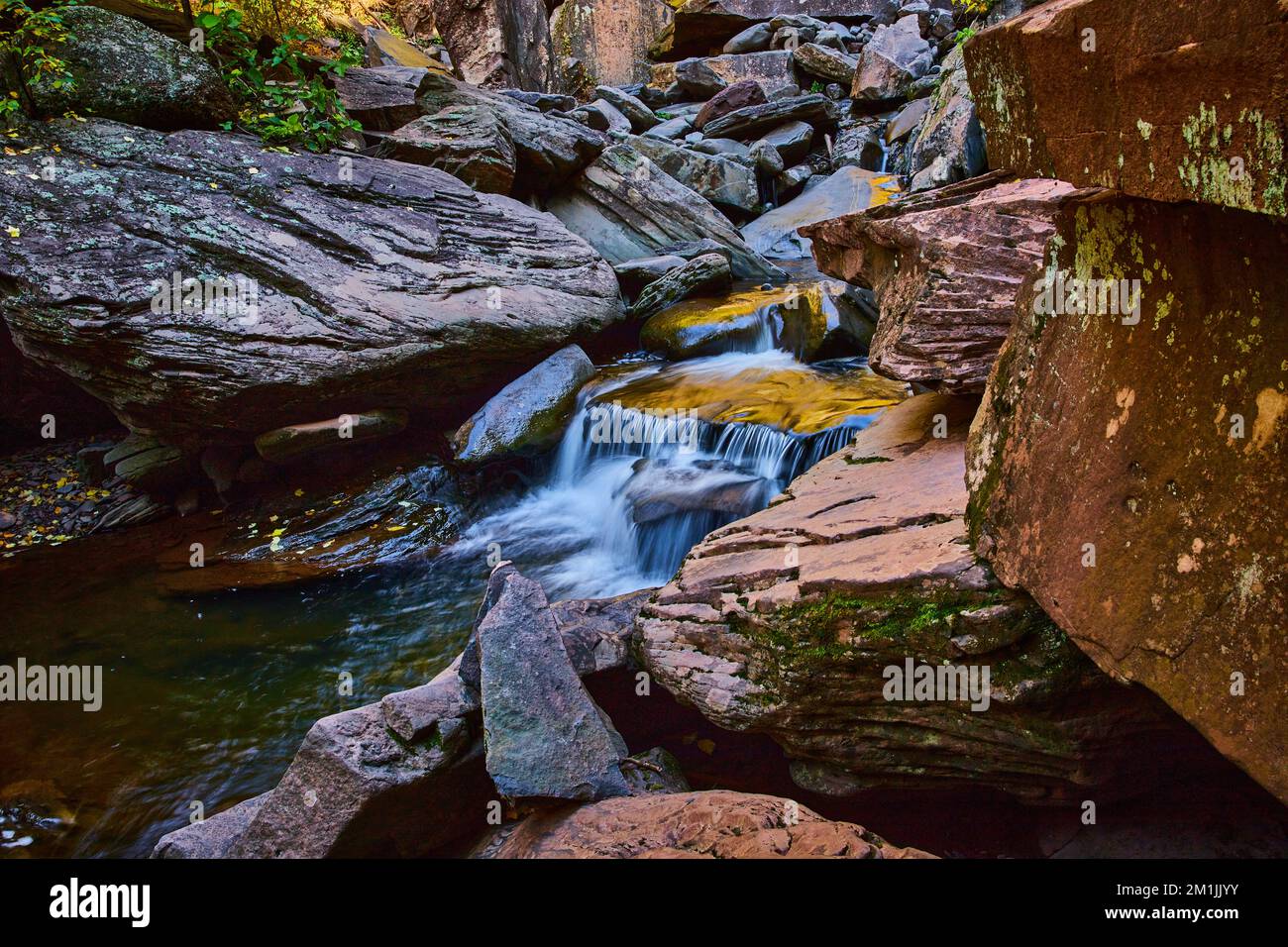 Detail of small cascading waterfall with rocky lichen boulders all ...
