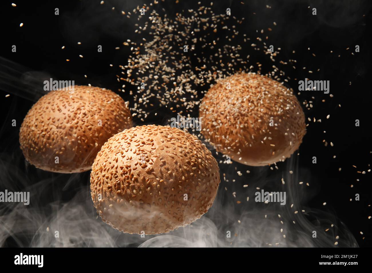 Flying burger buns with sesame and smoke on black background Stock ...