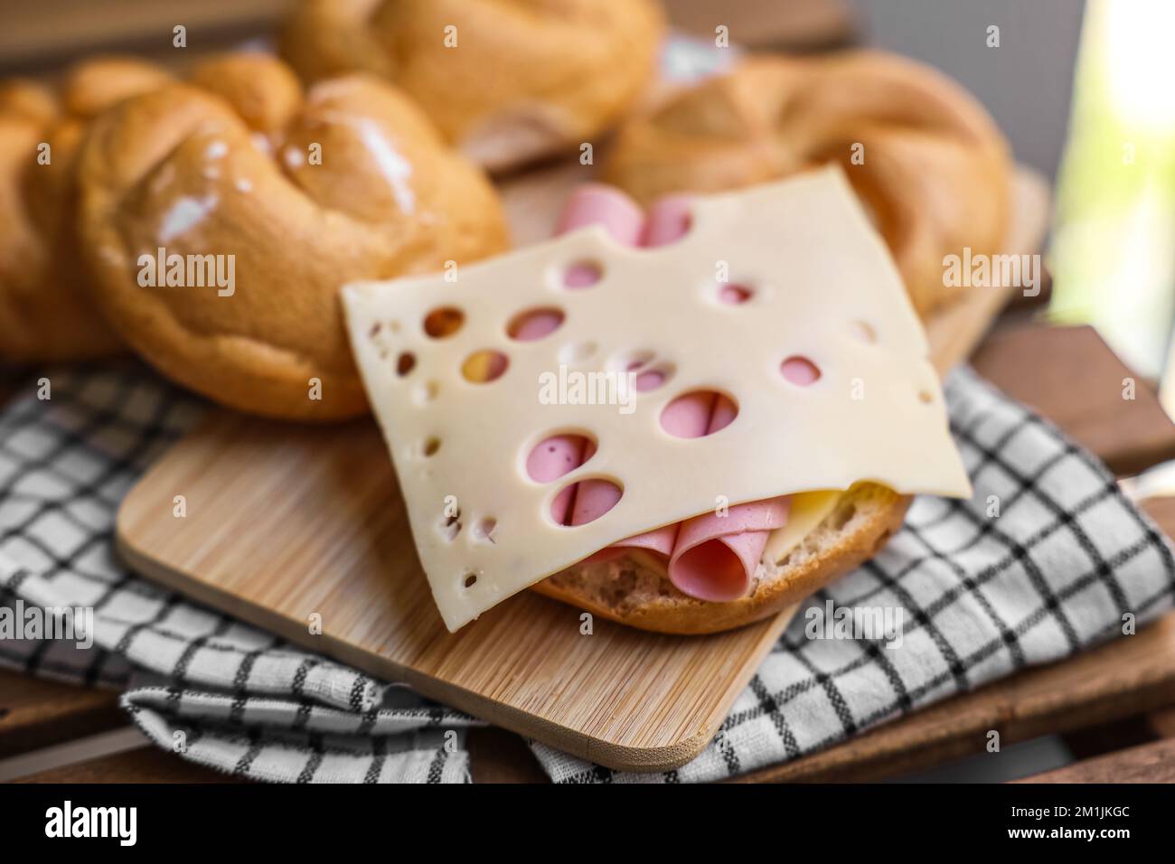 Delicious kaiser rolls with ham and cheese on wooden board Stock Photo ...