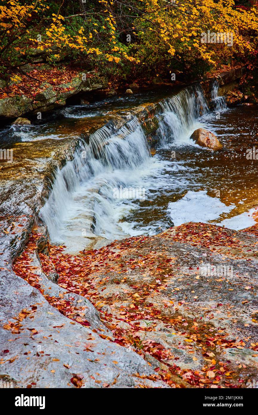 Cascading small waterfalls in river with exposed rocks covered in fall ...