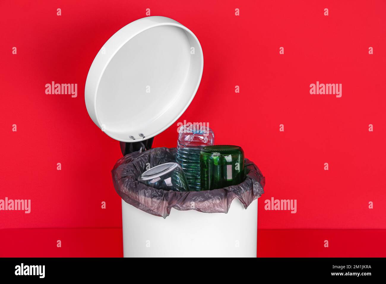 Open rubbish bin with trash on red background Stock Photo - Alamy