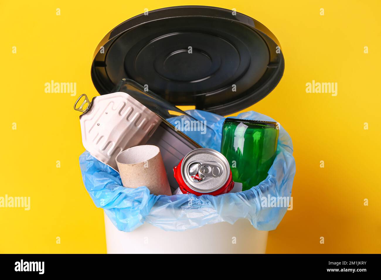Open rubbish bin with garbage on yellow background, closeup Stock Photo ...