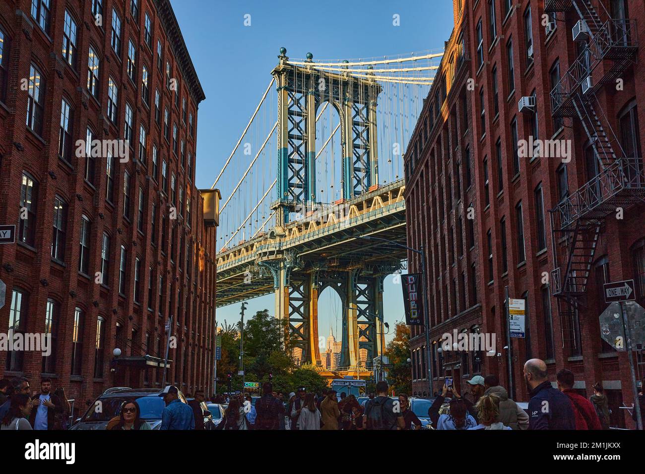 Pillar of Manhattan Bridge in sunlight framed by brick buildings and ...