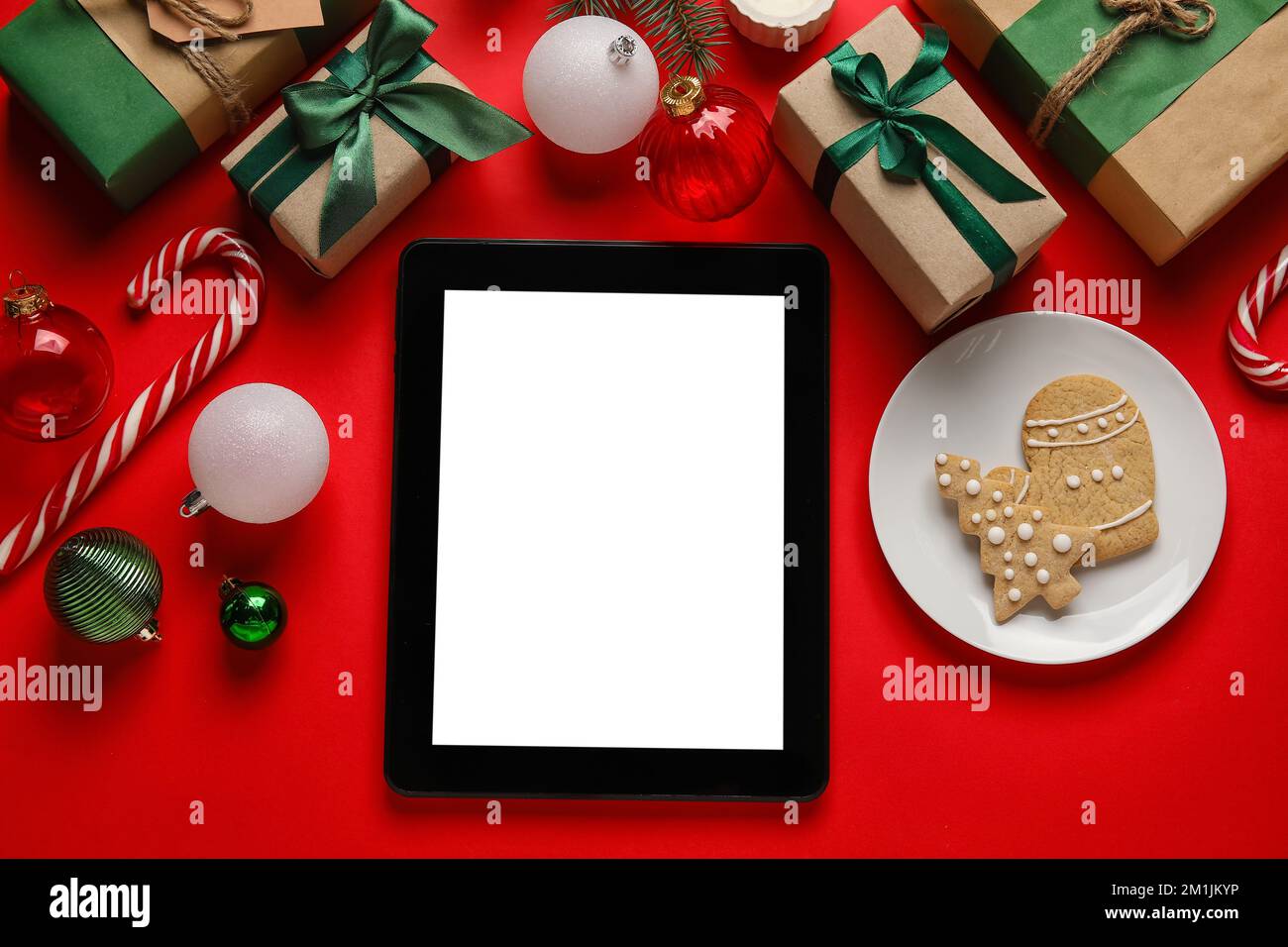 Blank tablet computer with Christmas cookies, gifts and decor on red ...