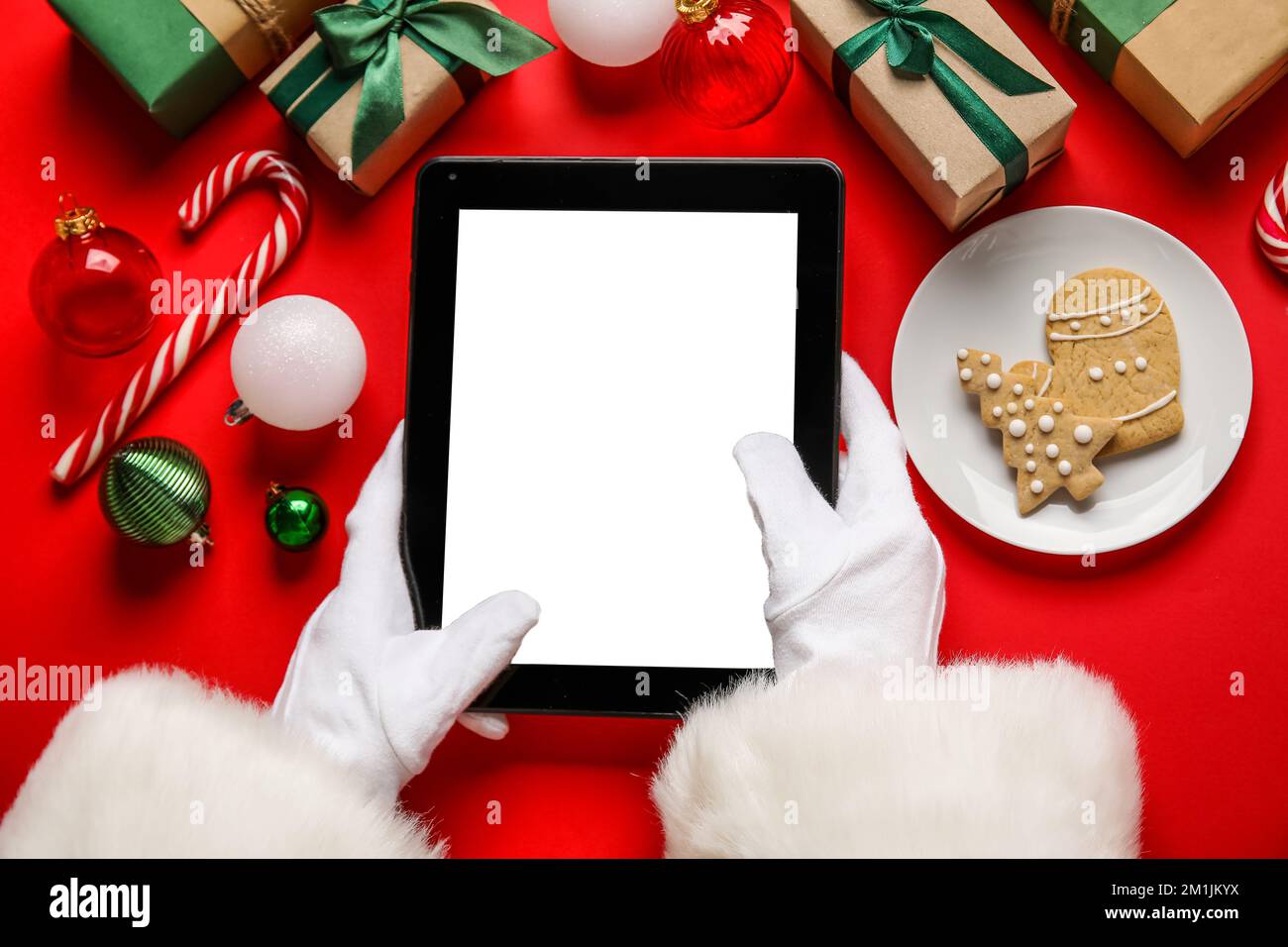 Santa Claus with tablet computer, cookies, gifts and Christmas decor on ...