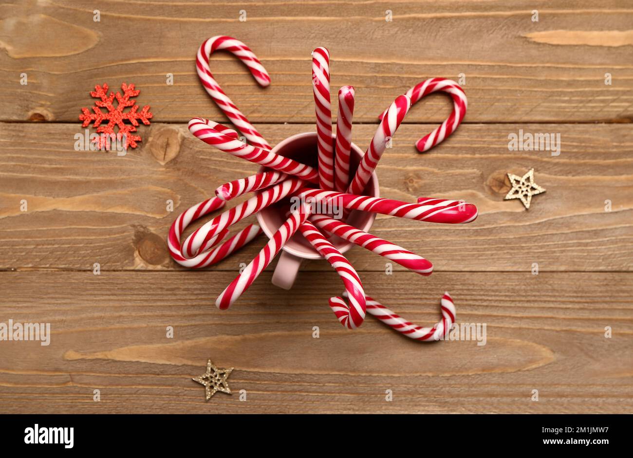 Cup with sweet candy canes and Christmas decor on wooden background ...