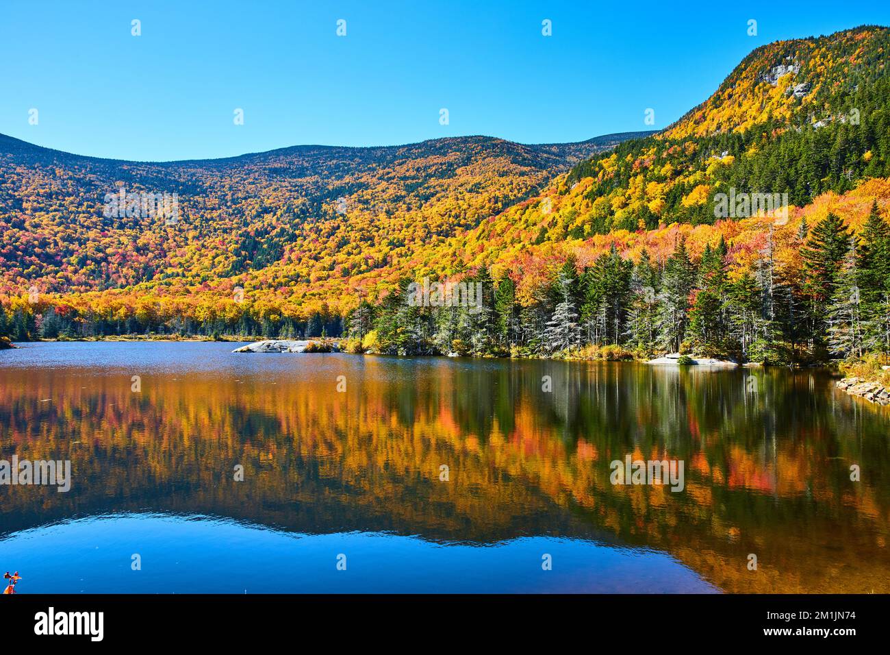 Beautiful lake reflecting mountains of fall foliage in New Hampshire ...