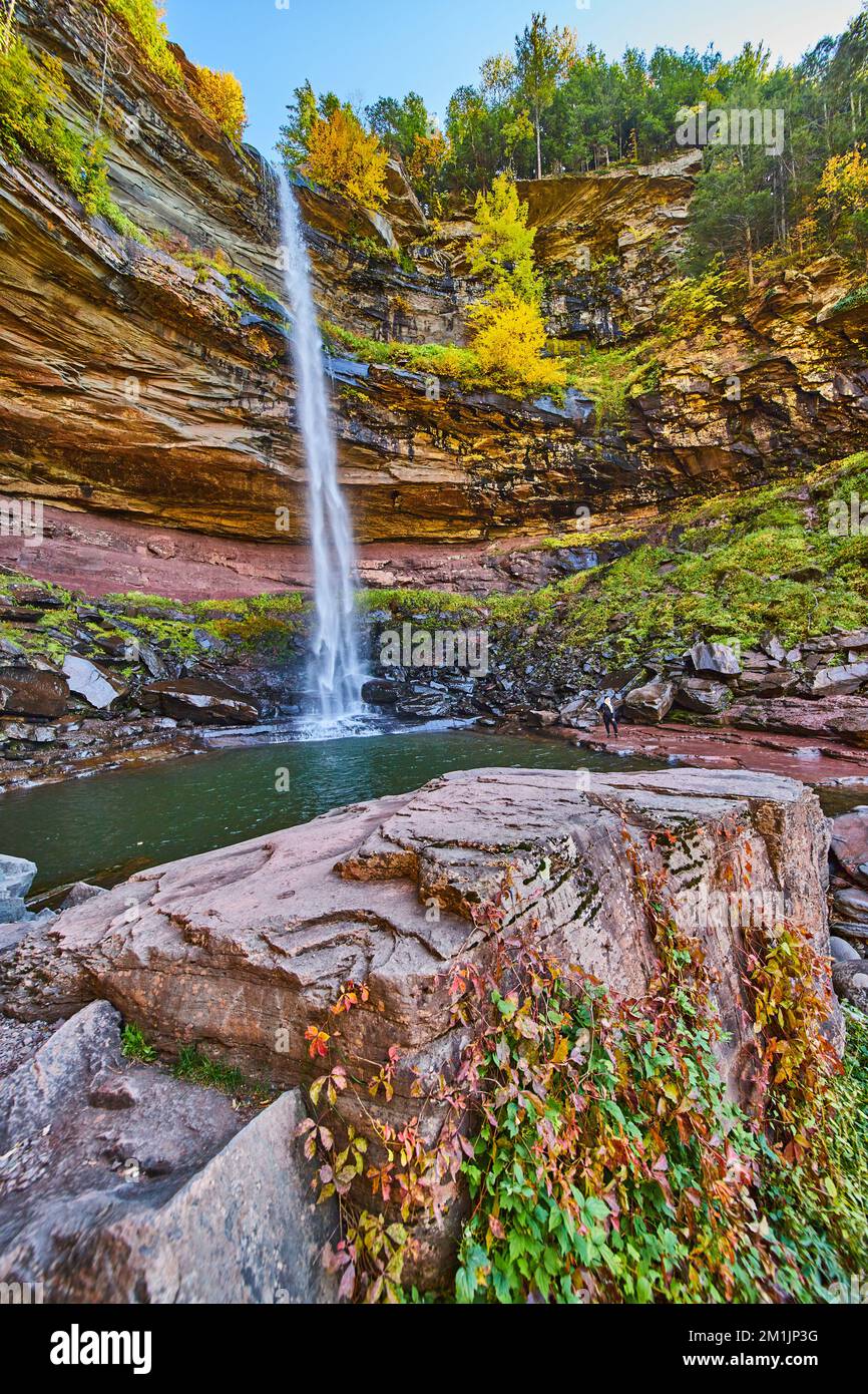 Beautiful tall waterfall over layered cliffs down to waters and large ...