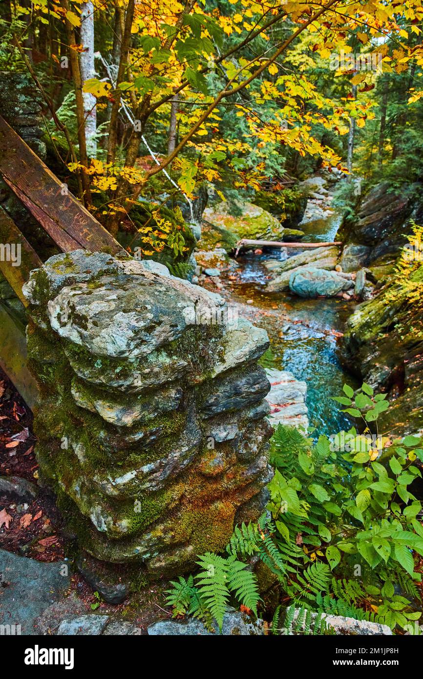 Stone block pillar covered in moss surrounded by fall forest river ...