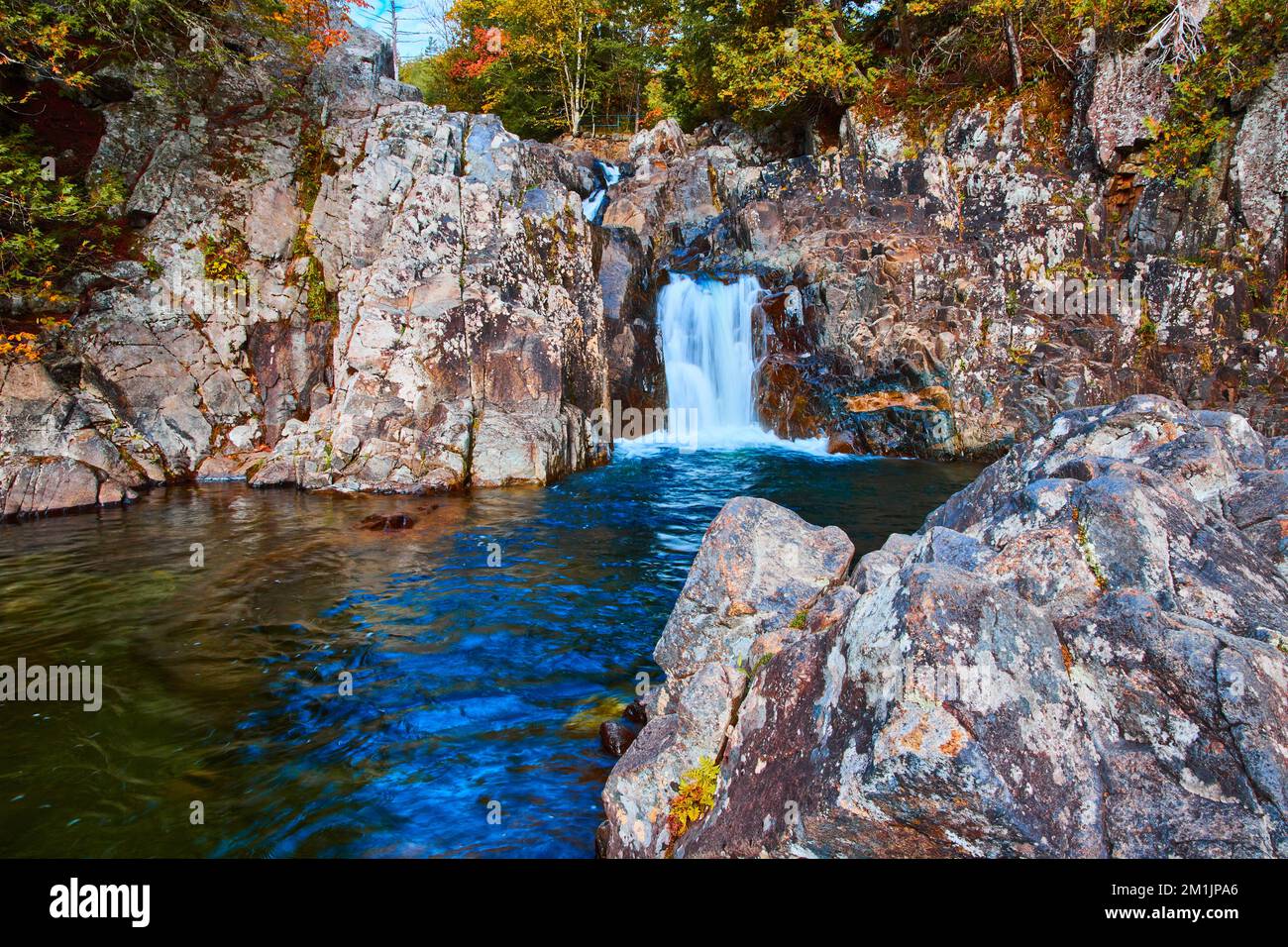 Tiers of waterfalls pouring over rocks into calm river from below in ...